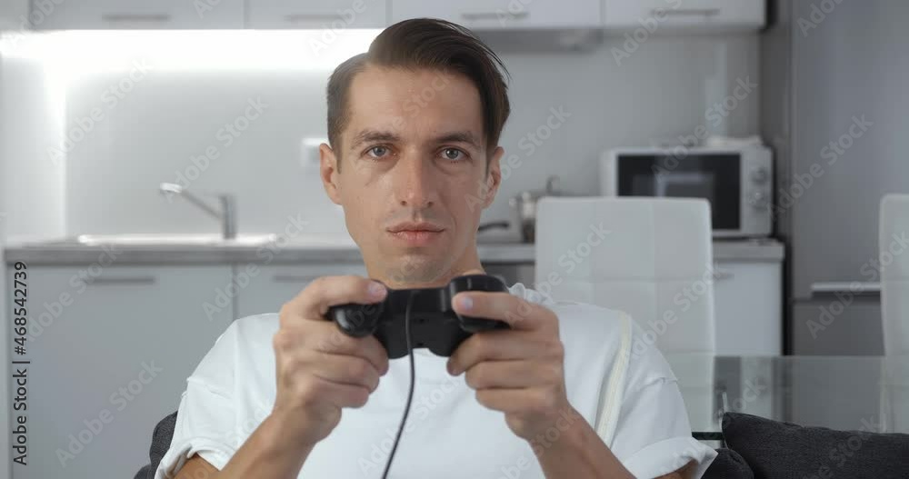 Happy man gamer holding controller playing video games while sitting on ...