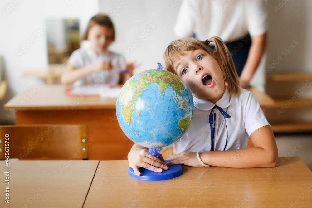 Funny girl student at a school desk with a globe Stock Photo | Adobe Stock