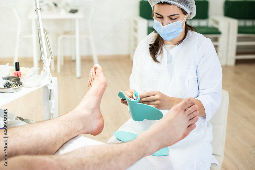 Professional men's pedicure in the salon. Young girl makes a man ...