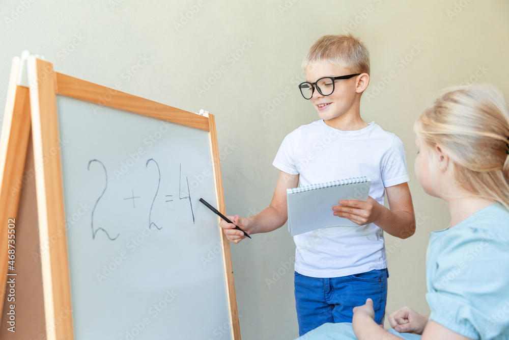 Children play school. A school-age boy explains a lesson to a girl ...