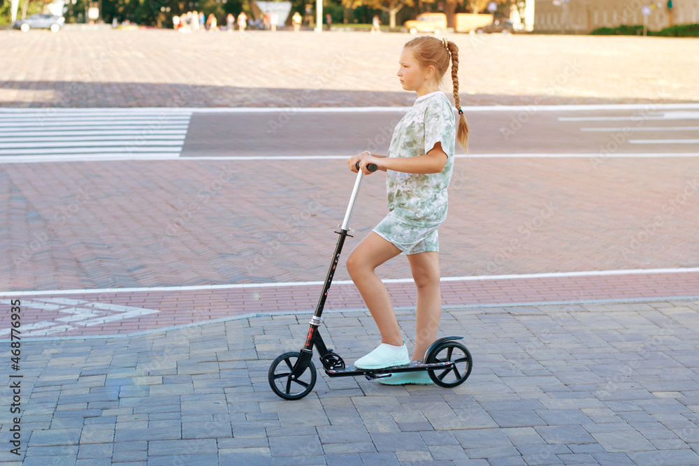 Cute teen girl rides around town on a scooter sunny summer day. Stock ...