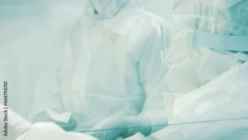 Handheld shot of a Caucasian female lab scientist in a full protective ...