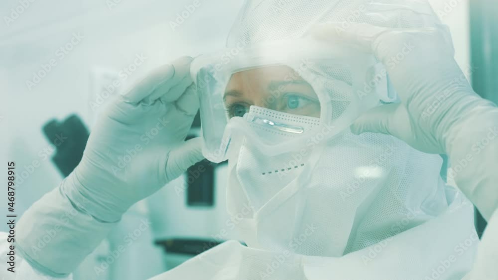 Close-up shot of a Caucasian female lab scientist, in a disposable ...