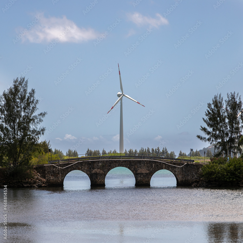 A single wind turbine stands behind the beautiful stone arched bridge ...