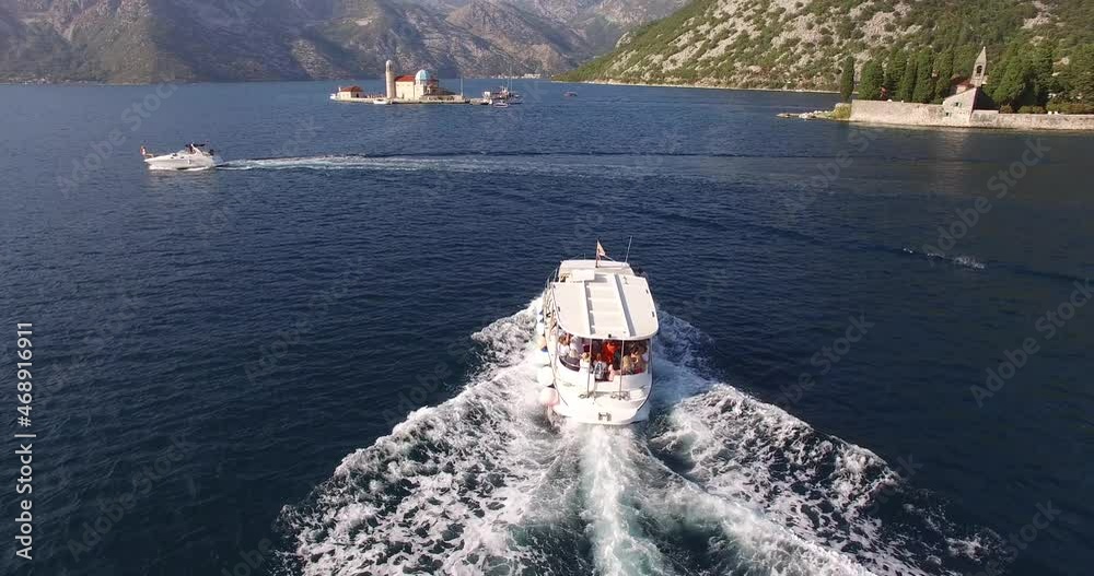 White motor boat floats on the sea past the islands of St. George and ...