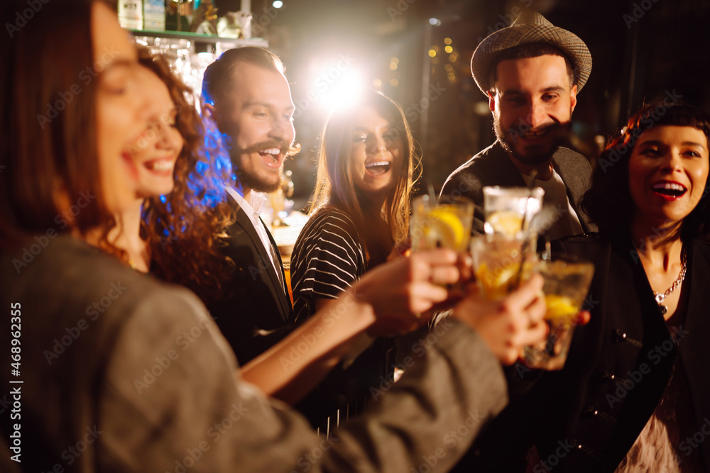 Cheering and drinking cocktails. Group of people partying in a ...