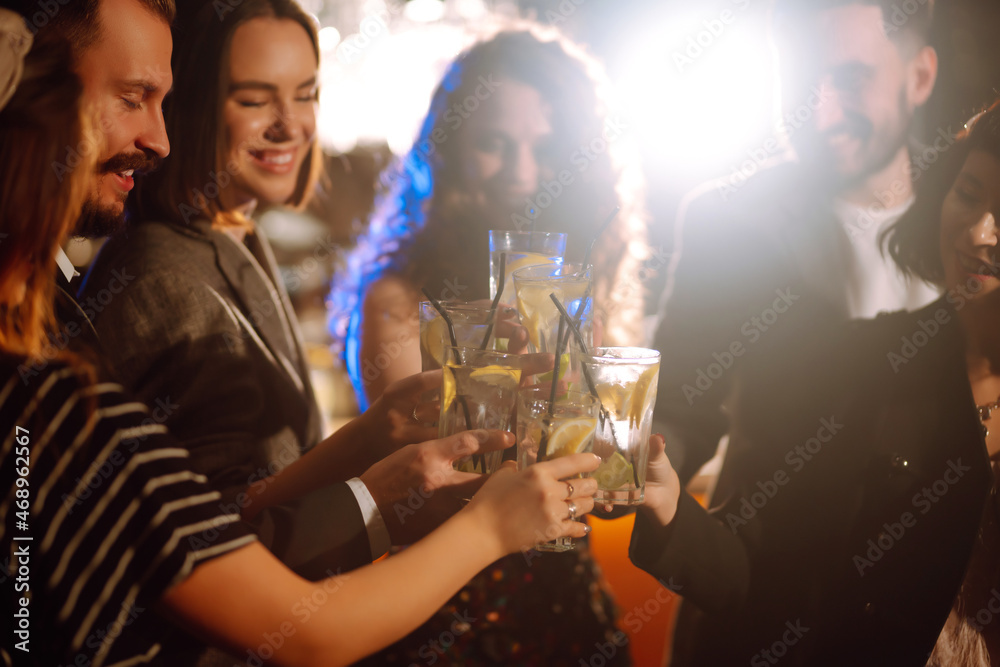 Cheering and drinking cocktails. Group of people partying in a ...
