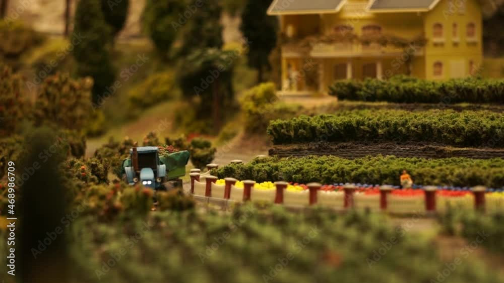 A tractor model with a trailer moves through the countryside. Footage ...