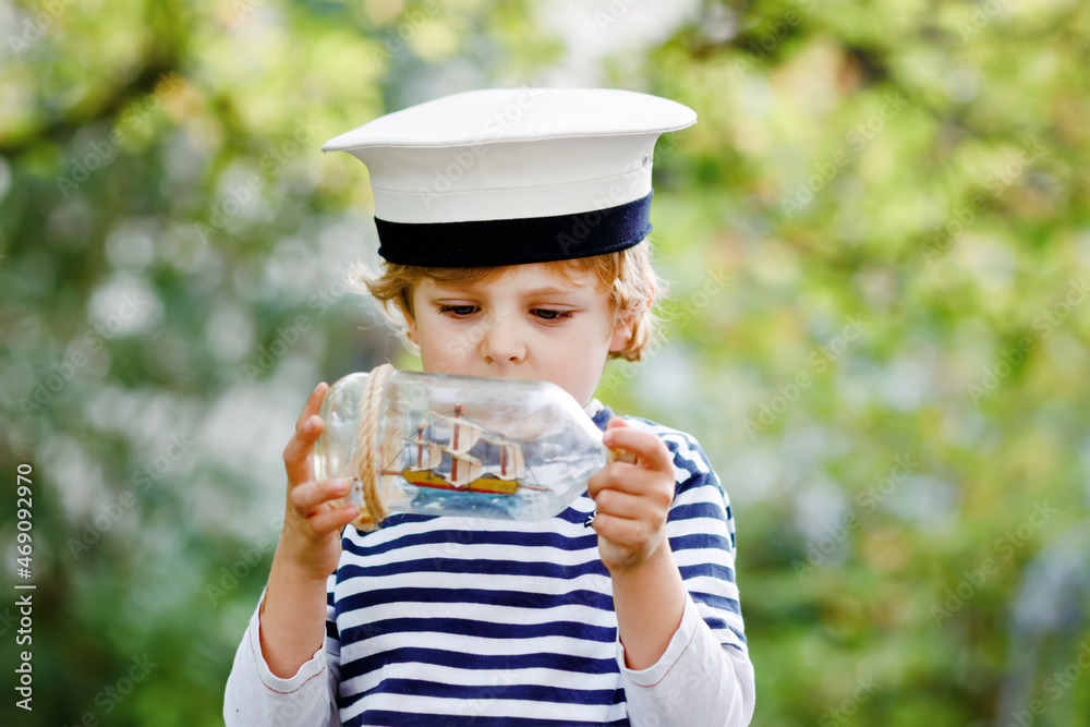 Happy little kid boy in sailor capitain hat and uniform playing with ...