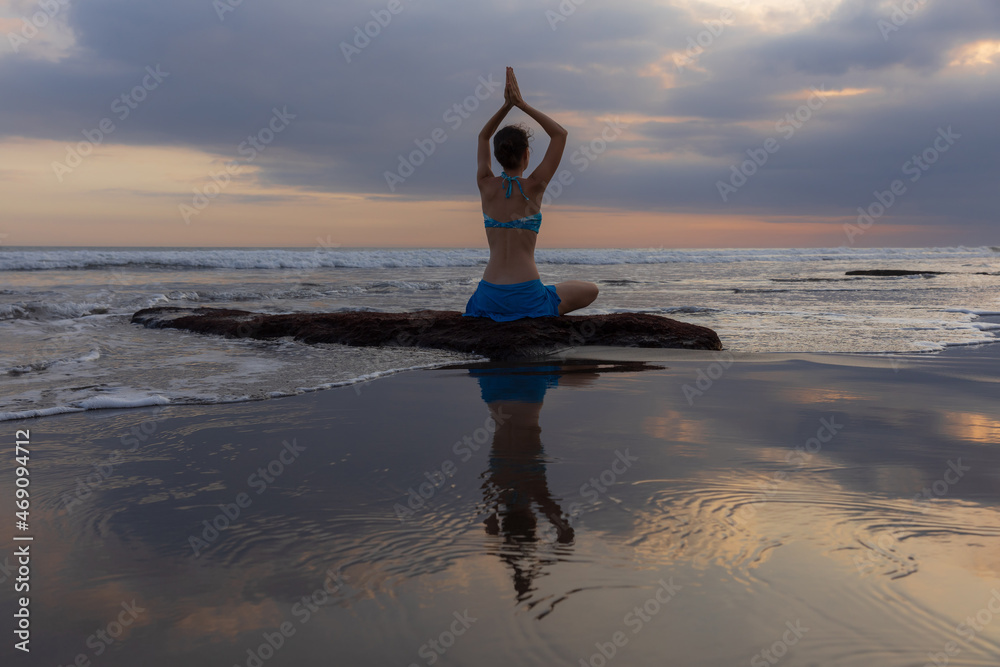 Sunset yoga. Caucasian woman sitting on the stone in Lotus pose ...
