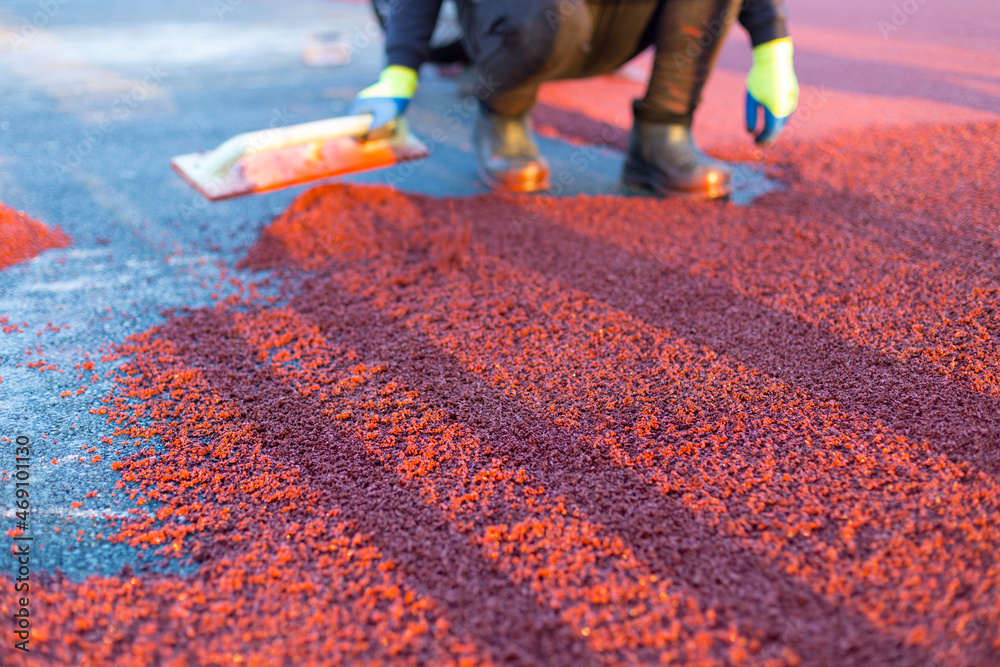 red rubber covering for the playground, the master smoothes the soft ...