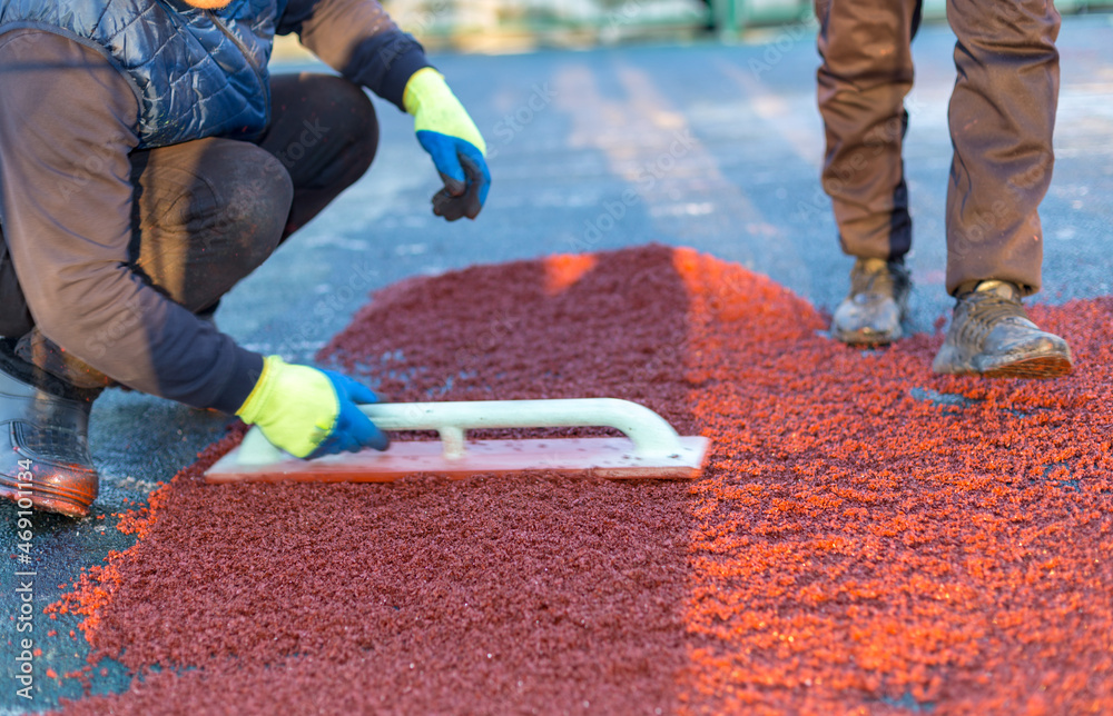 red rubber covering for the playground, the master smoothes the soft ...