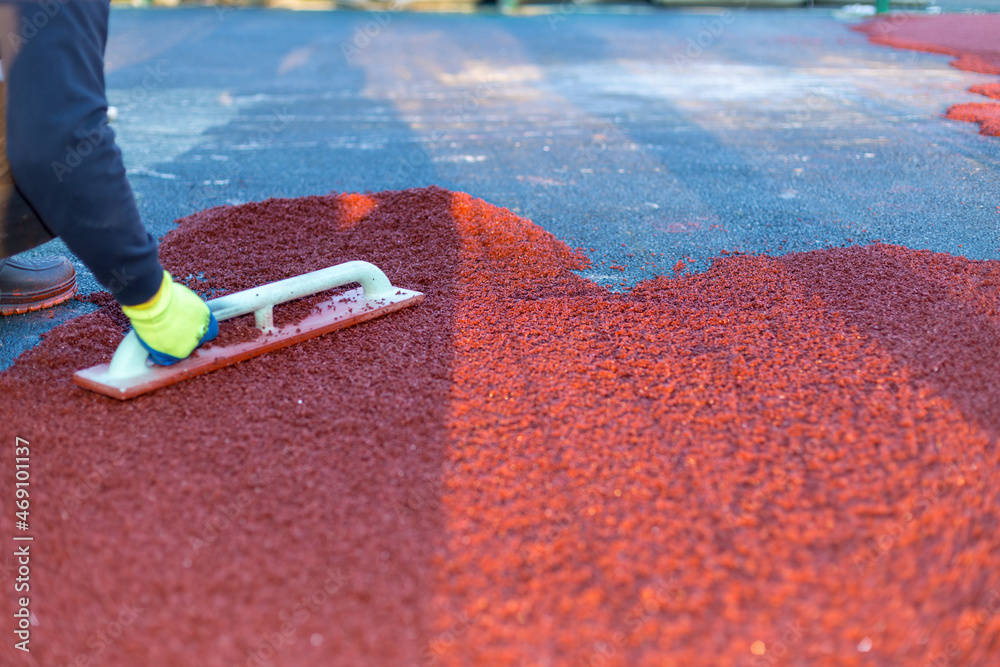 red rubber covering for the playground, the master smoothes the soft ...