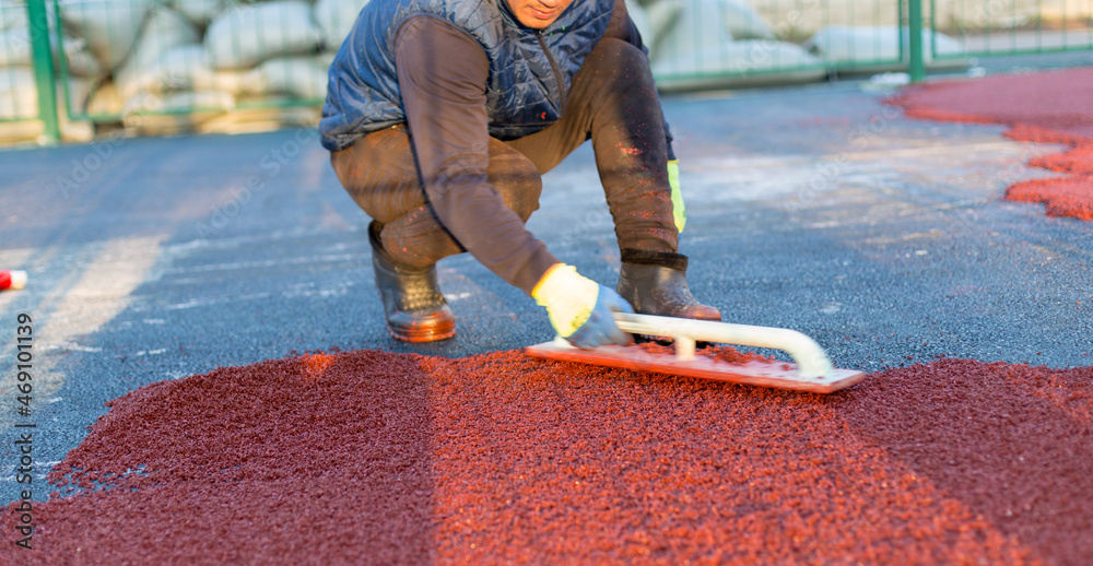 red rubber covering for the playground, the master smoothes the soft ...