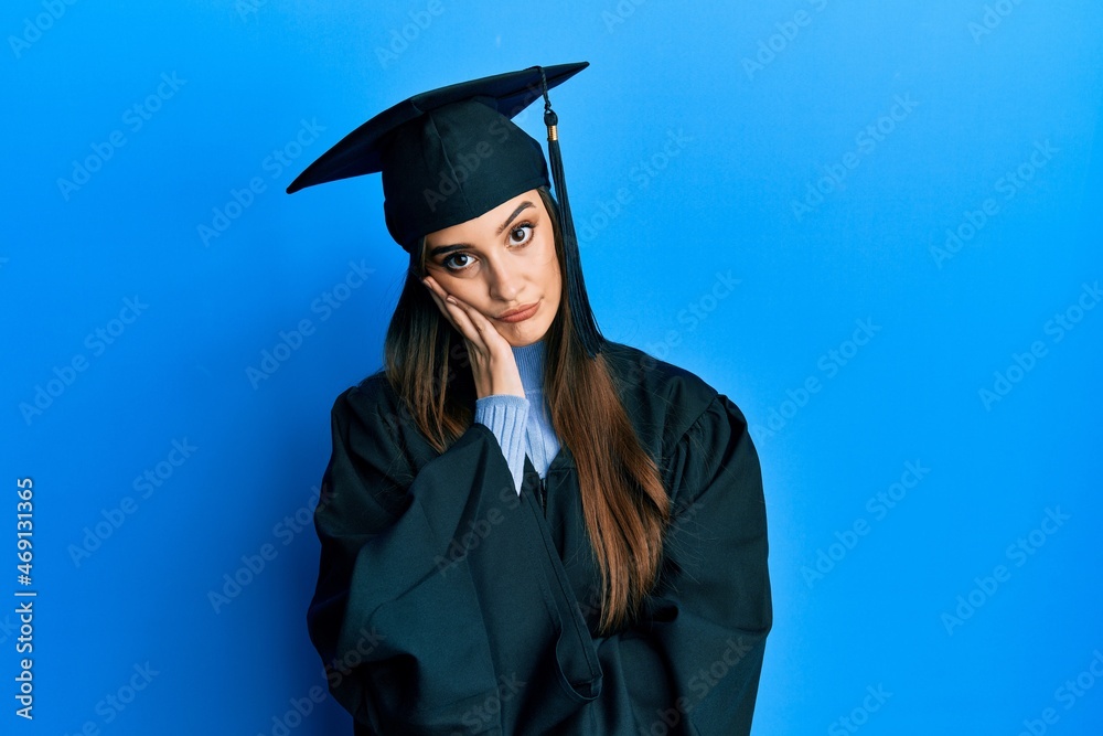Beautiful brunette young woman wearing graduation cap and ceremony robe ...