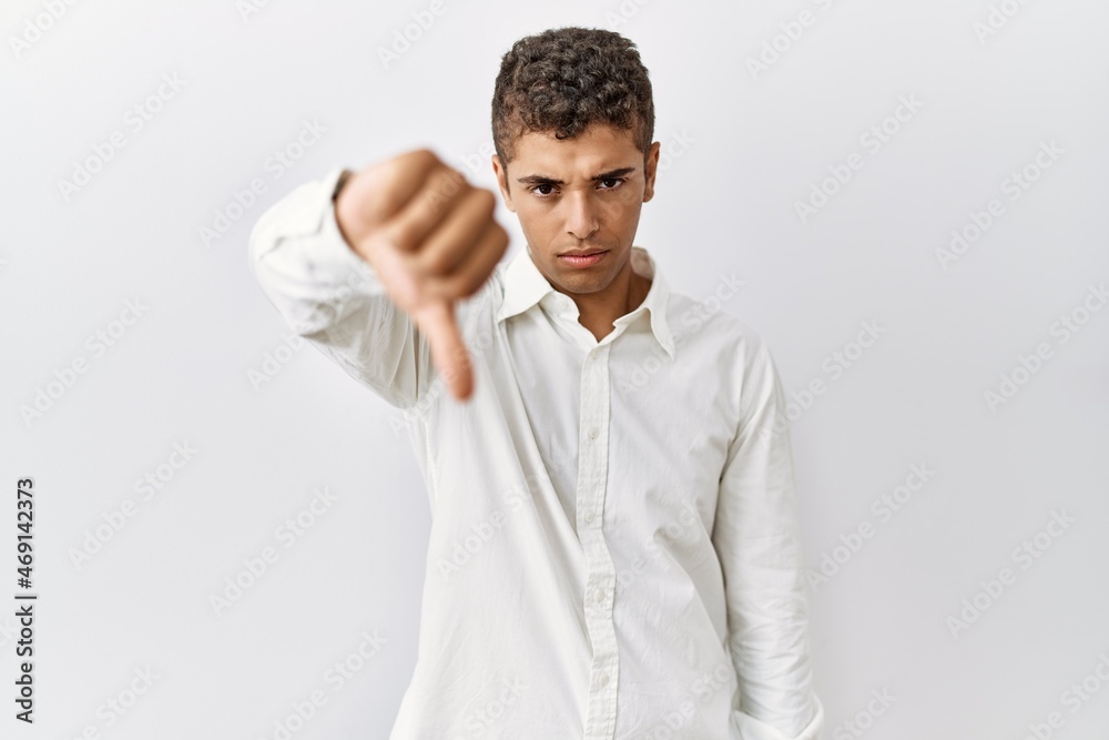 Young handsome hispanic man standing over isolated background looking ...
