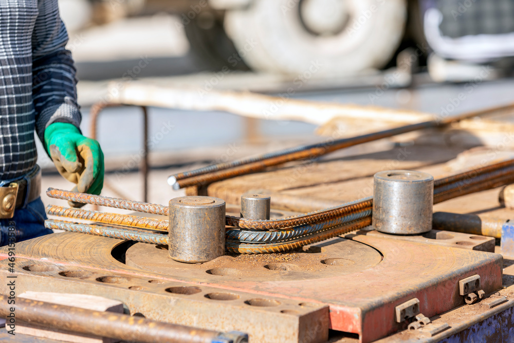 Construction worker is bending to rebars with tool. Rebar, also known ...