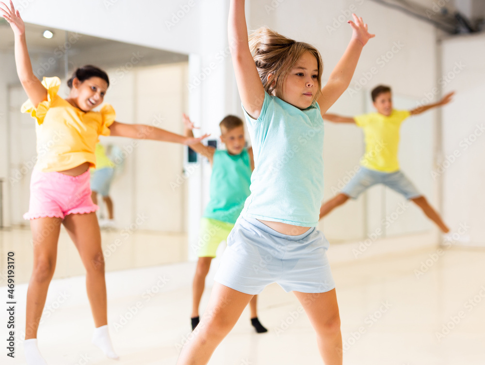 Happy cute sporty tween girl exercising in modern choreographic studio ...