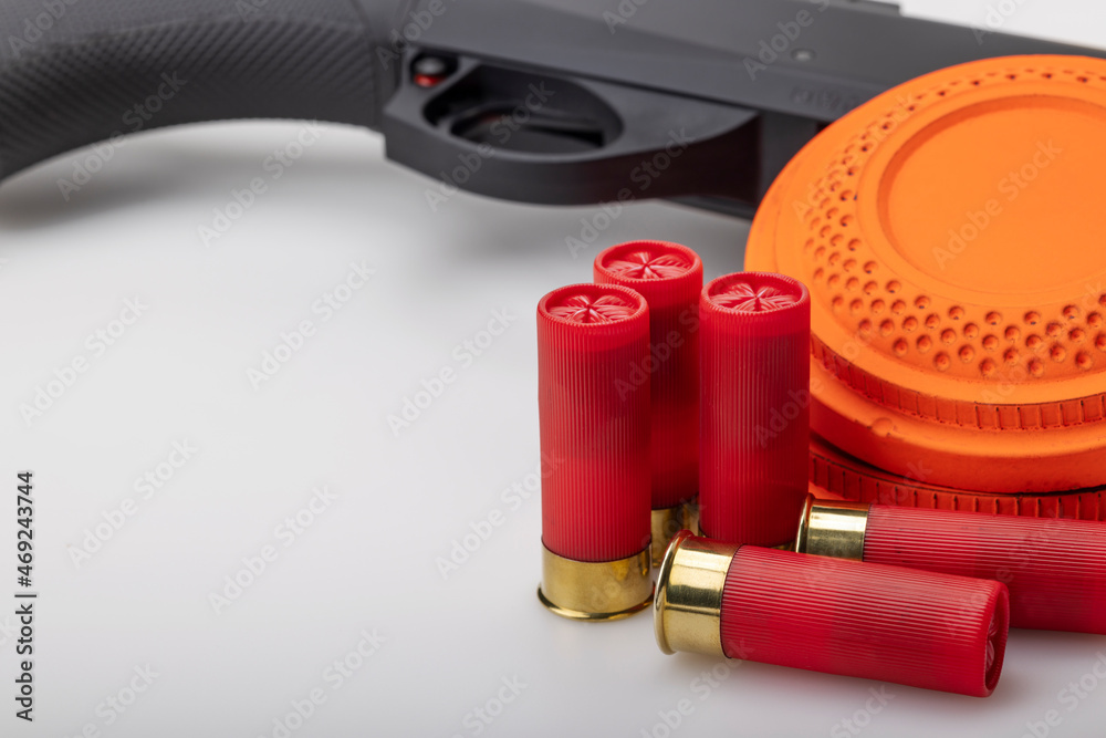 Clay disc flying target and shotgun with bullet shell on white ...