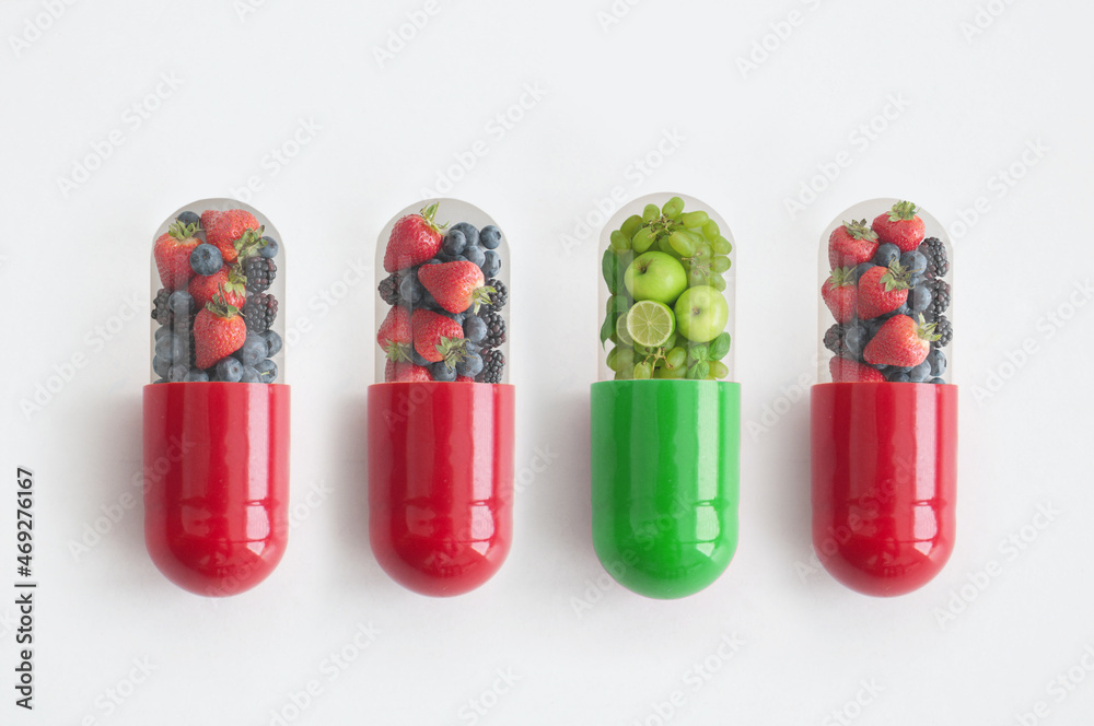 Unique green vitamin pill supplement amongst red fruit pills, food ...