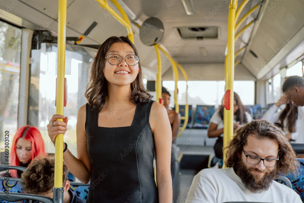 Smiling, attractive student in strange city, moving by public transport ...