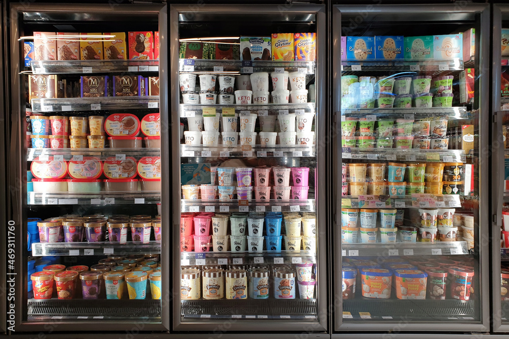 Interior view of huge glass fridge with various brand ice cream in ...