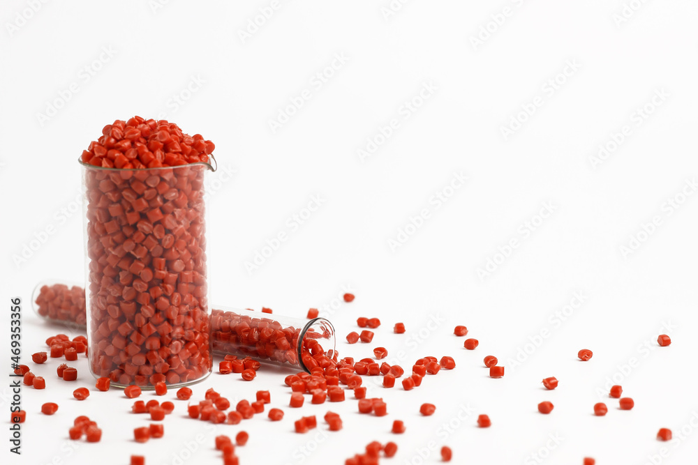 Red granules of polypropylene, polyamide in a measuring beaker and a ...