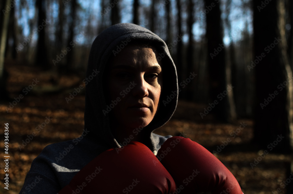 Young beautiful woman boxer in a tracksuit with a hood on his head in ...
