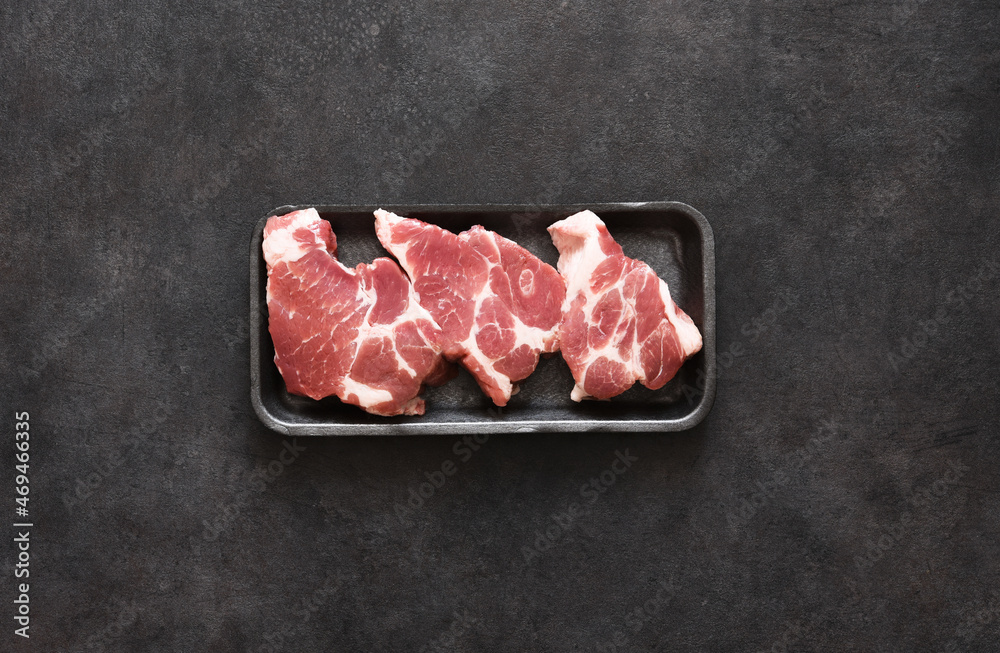 Three beef steaks with a tray on a black background, top view. Pulp ...