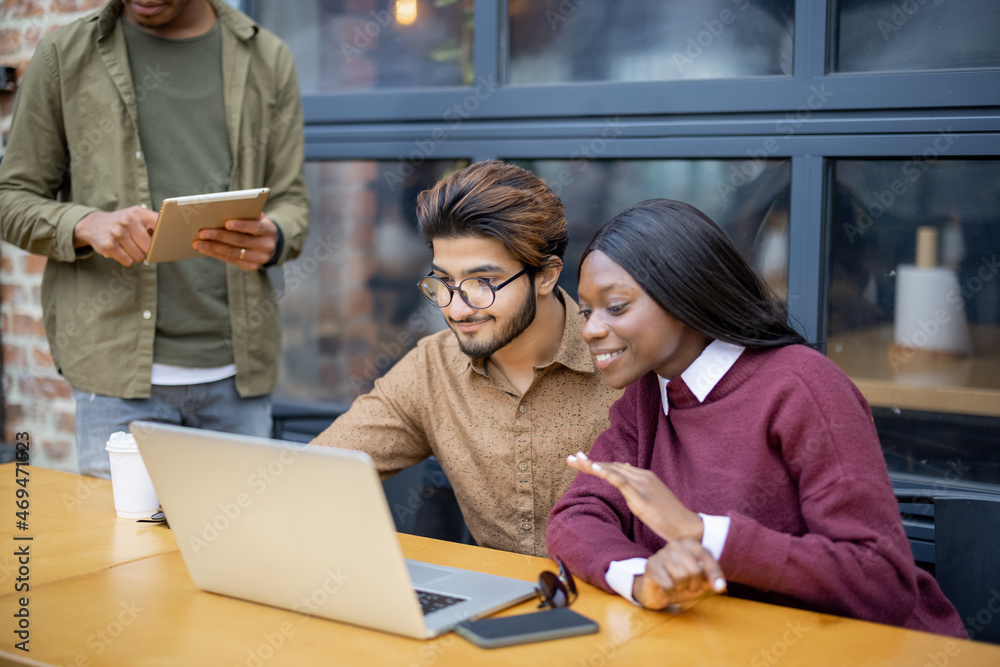 Multiracial students having video call on laptop at table outdoors ...