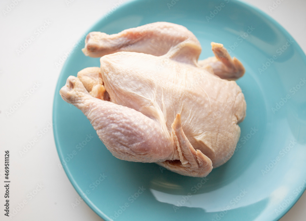 broiler chicken carcass, with skin, on a plate, on a light background ...