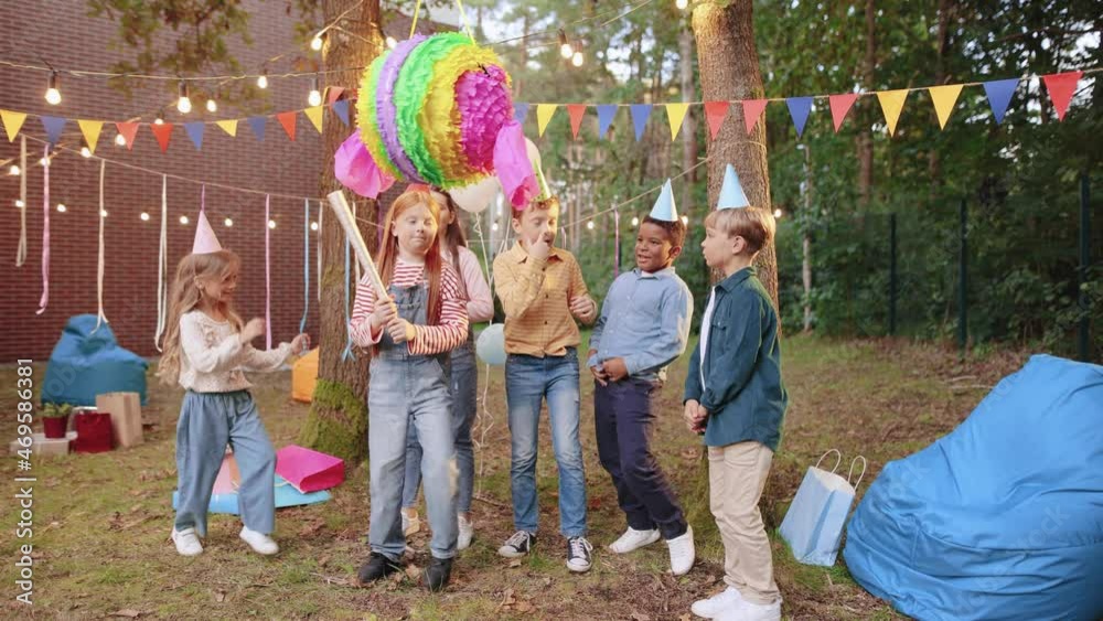 Group of kids smashing with a bat colorful piñata in the spring field ...