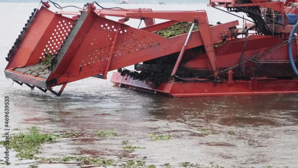 Worker on a weed clearing water tractor (or aquatic weed harvester ...