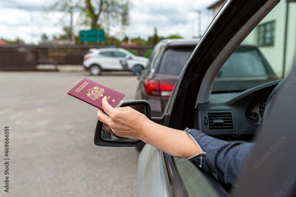 women hand through car window giving passport for customs control, rear ...