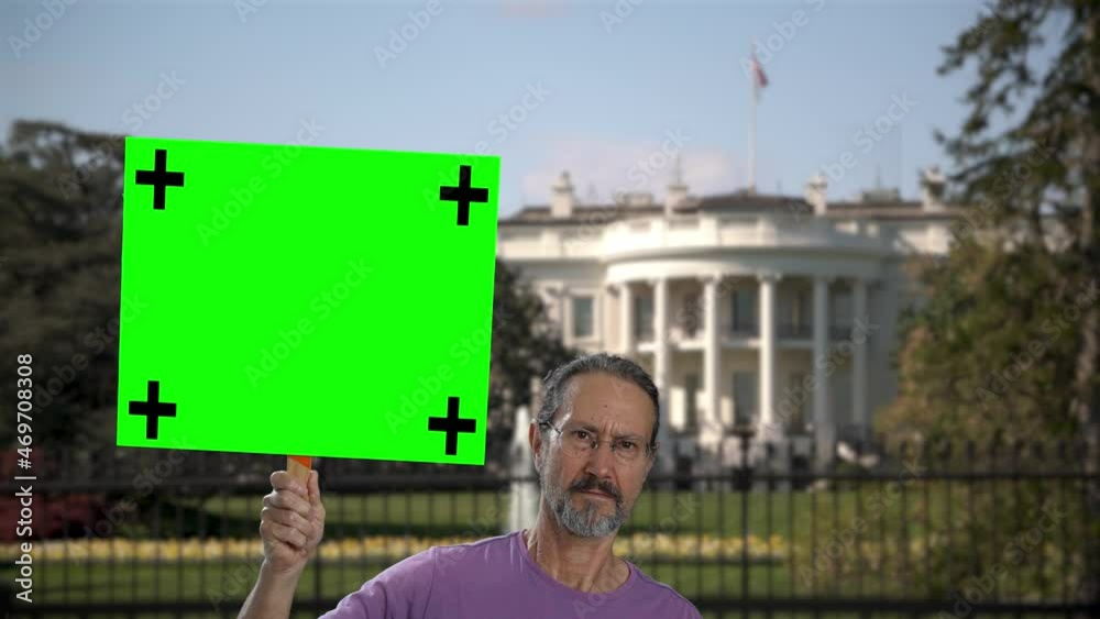 Man holds a blank green screen chroma key sign for protest outside ...
