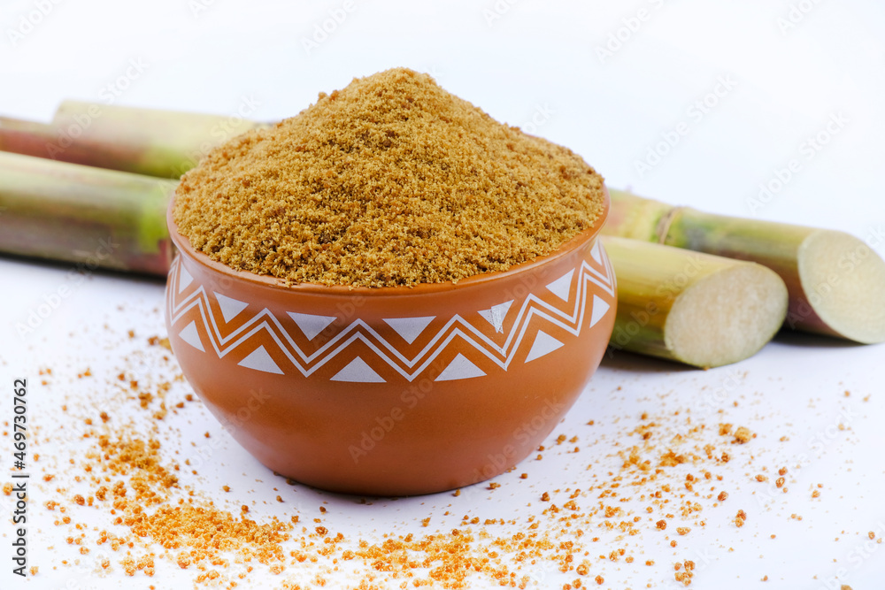 Jaggery powder and sugarcane isolated on white background. Jaggery is ...