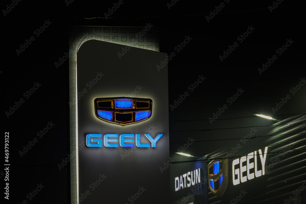 Geely logo on car dealership pillar and building at foggy night - Geely ...