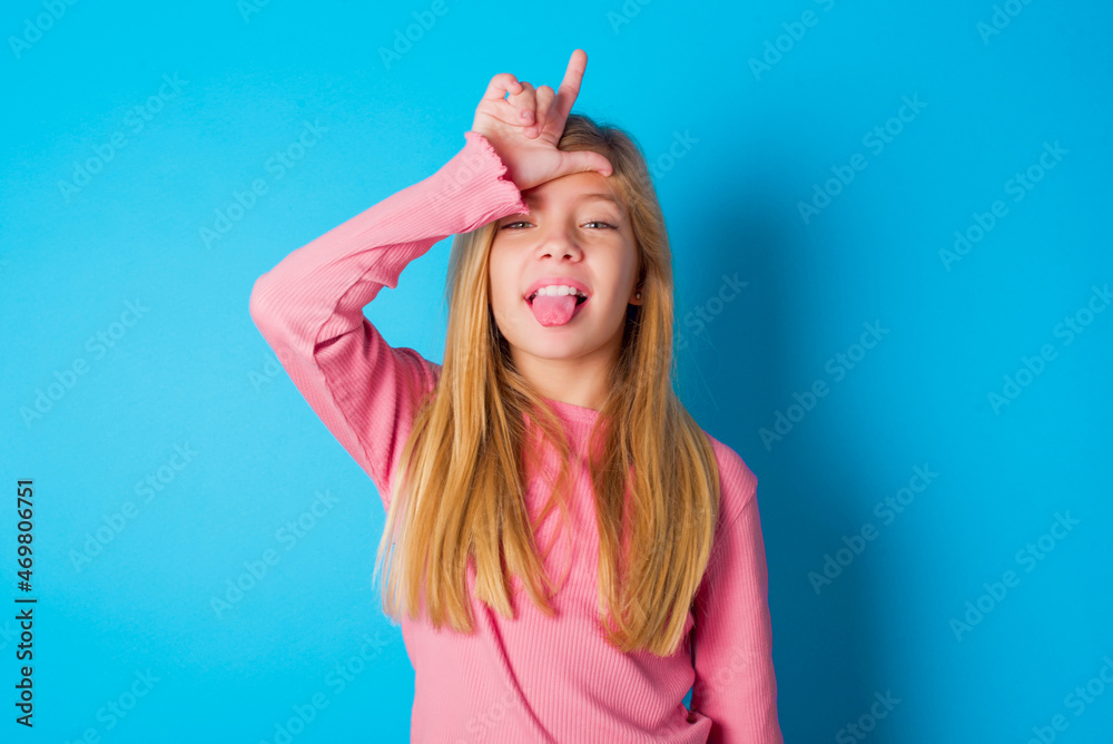 Funny caucasian little kid girl wearing long sleeve shirt over blue ...