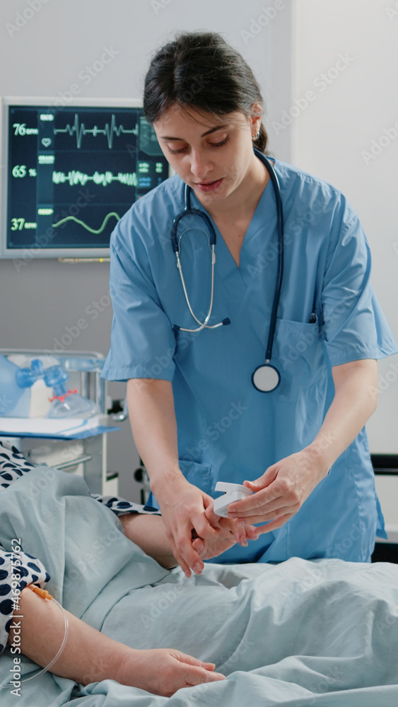 Medical assistant putting oximeter on finger of aged patient in ...