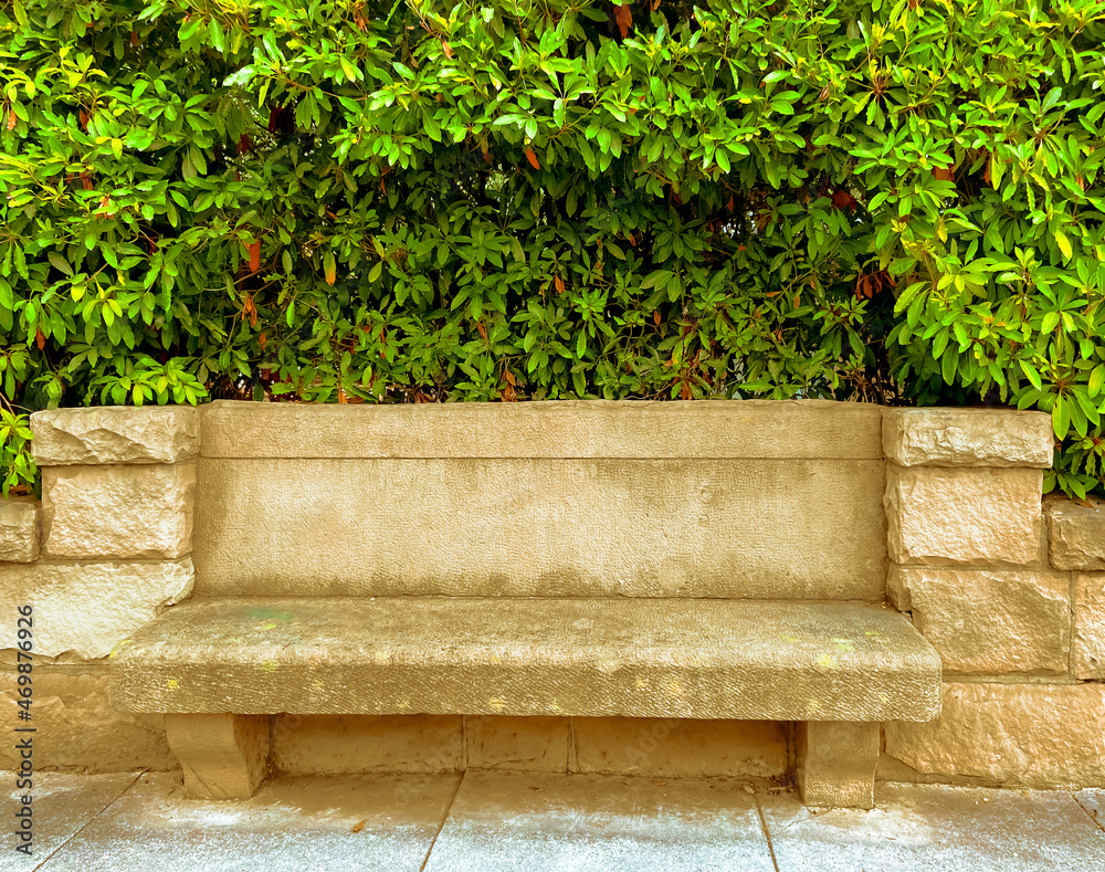 Old bus stop bench, built out of sandstone bricks under a green hedge ...