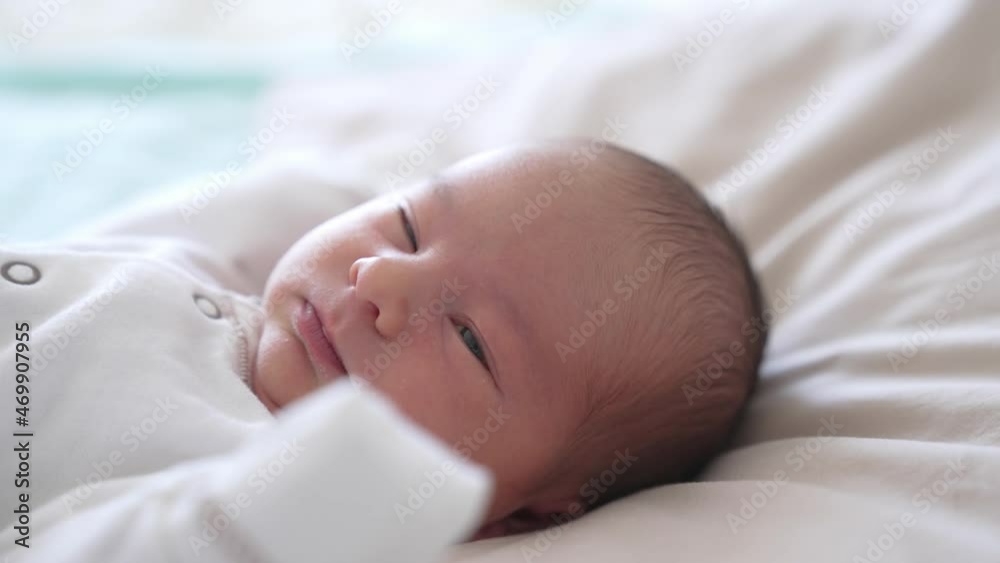 Tiny child is slowly blinking its eyes and gradually falling asleep ...