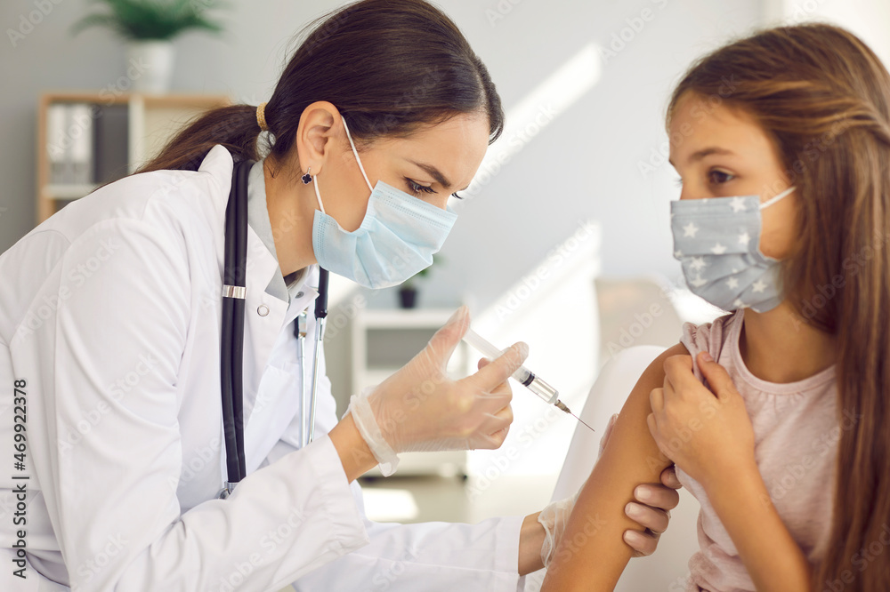Nurse in white gloves holding a syringe and giving a shot to a child ...