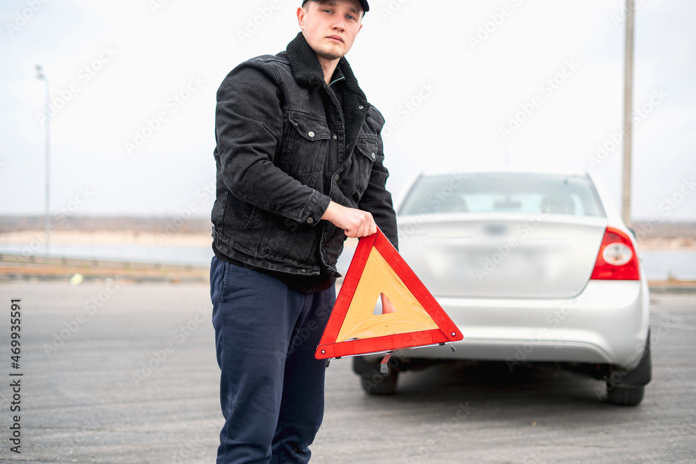 male driver puts red triangle warning sign on the road as the symbol of ...