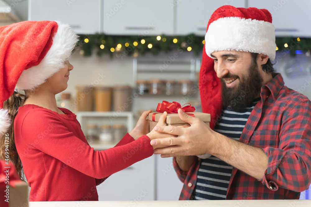 Happy father and daughter in Santa hat have fun giving Christmas gifts ...
