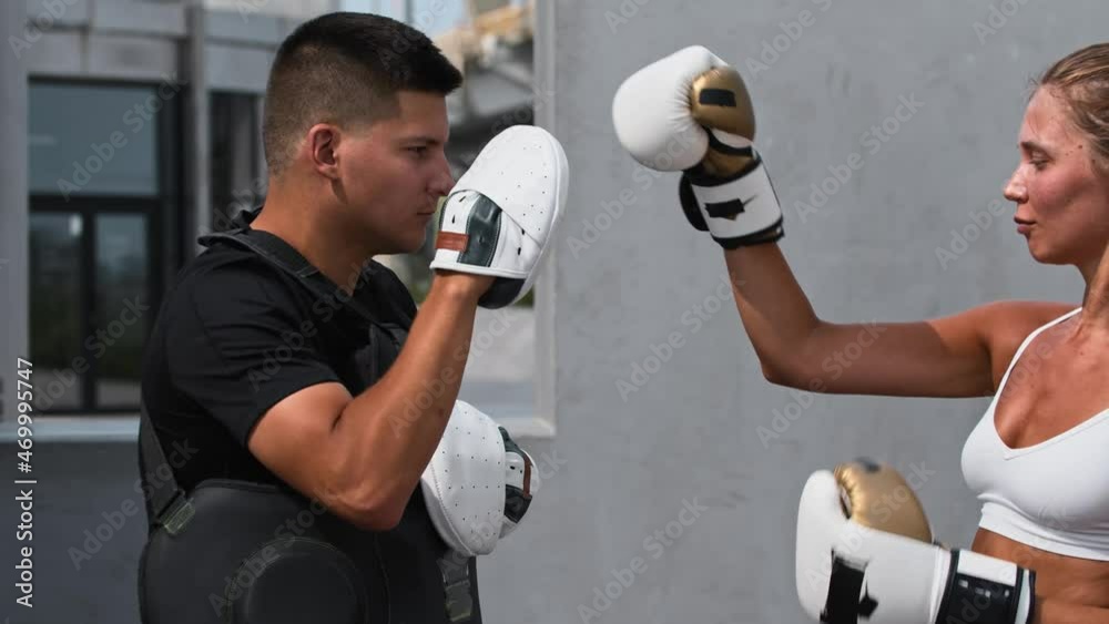 Young woman having a boxing training outdoors with a male trainer ...