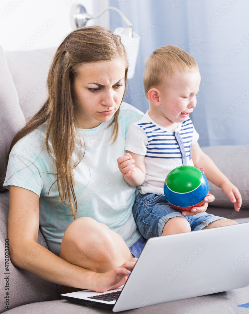 Perplexed mother is having issue with work while child crying at home ...
