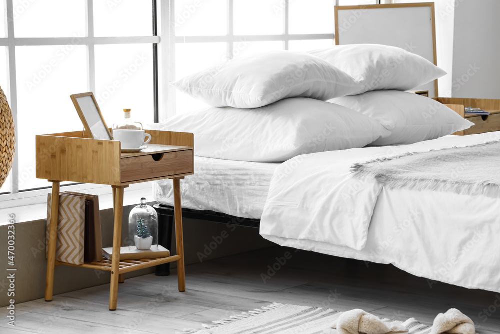 Wooden bedside table and bed near window in room Stock Photo | Adobe Stock