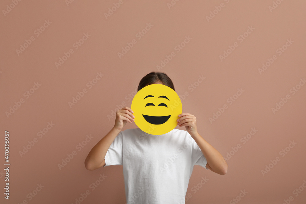 Little girl covering face with laughing emoji on pale pink background ...
