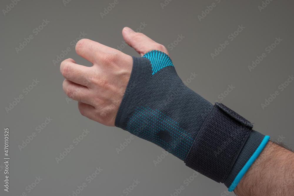 Velcro wrist stabilizer cast worn by Caucasian male hand. A blue split ...