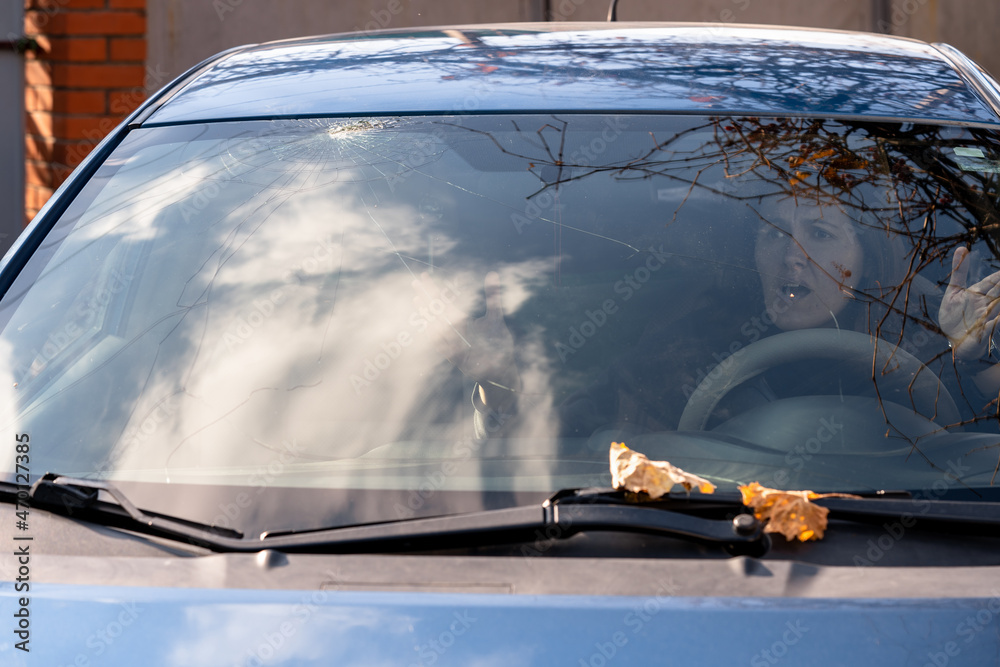 Shocked woman in car with broken windshield and cracks. Car accident ...